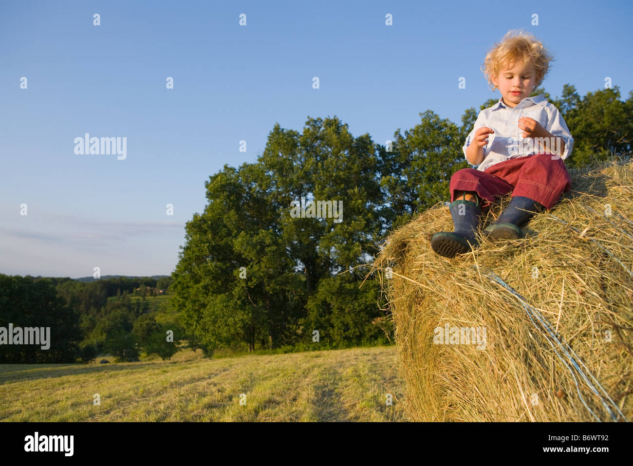A boy sitting on a haystack Stock Photo - Alamy