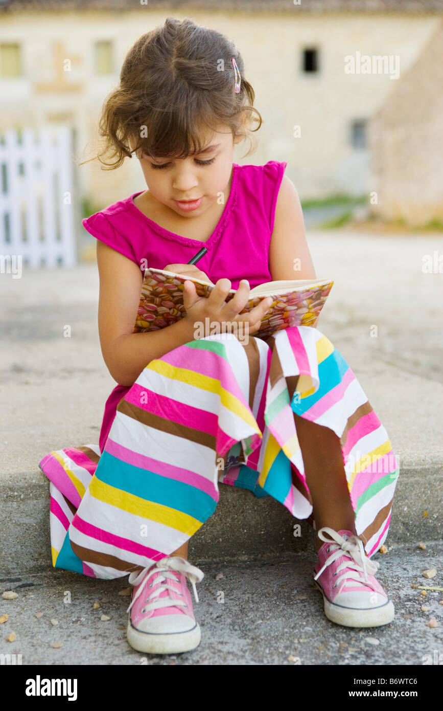 A girl writing in a book Stock Photo - Alamy