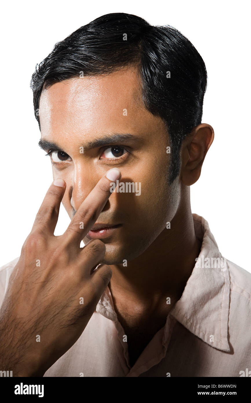 Young man pointing at his eyes Stock Photo - Alamy