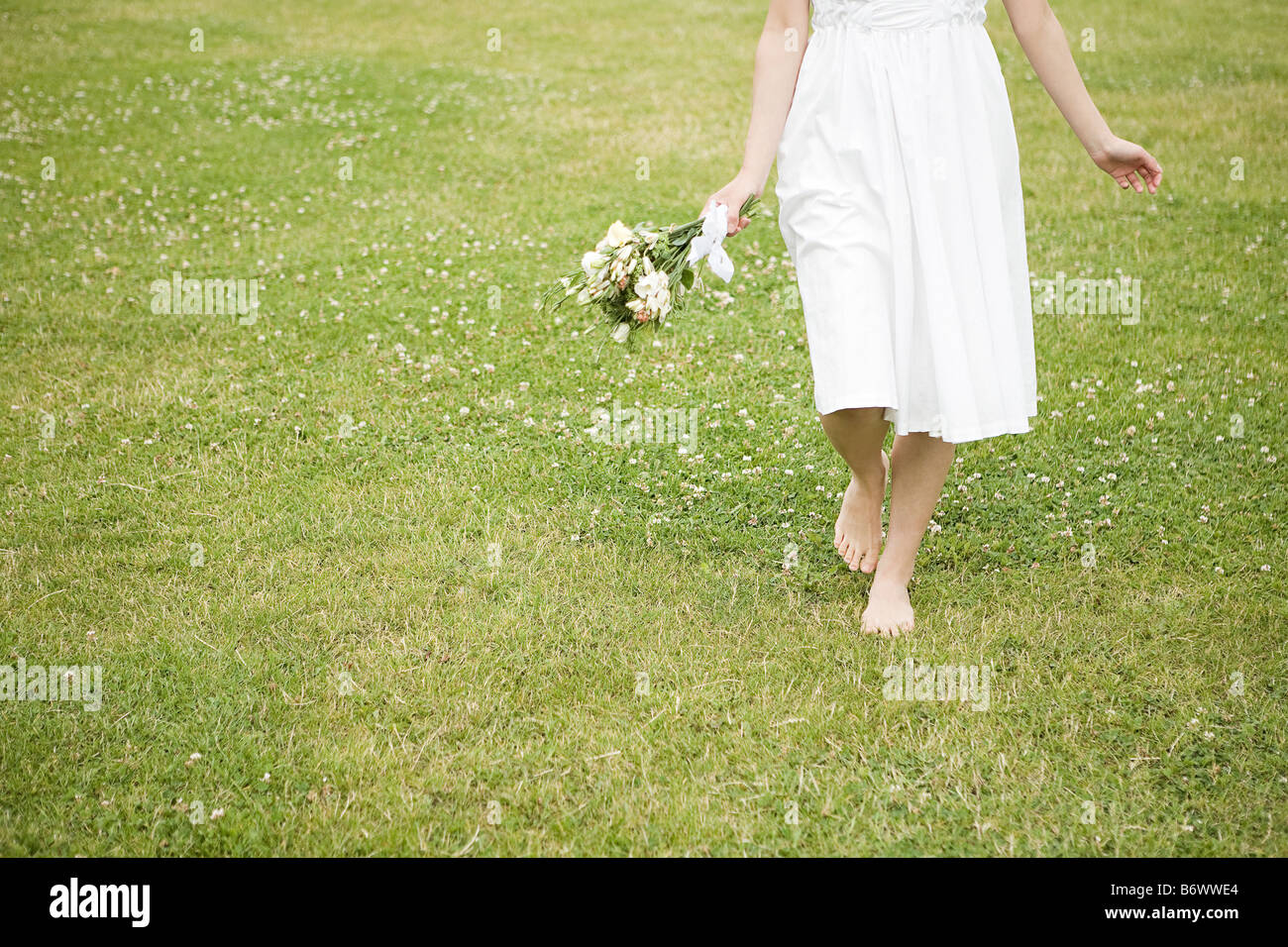 Bride walking on grass Stock Photo - Alamy