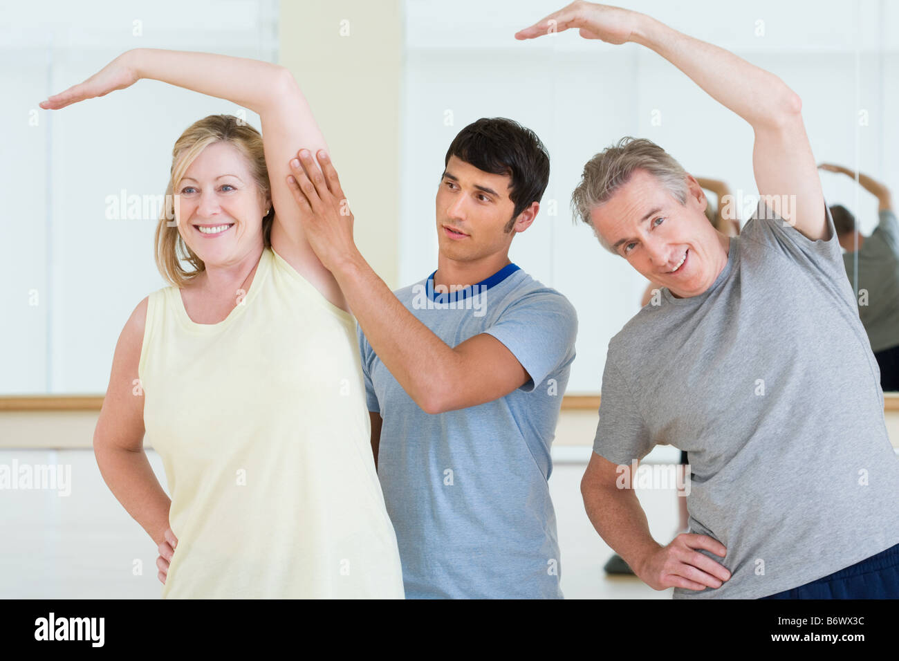 A personal trainer helping a woman in an exercise lesson Stock Photo ...