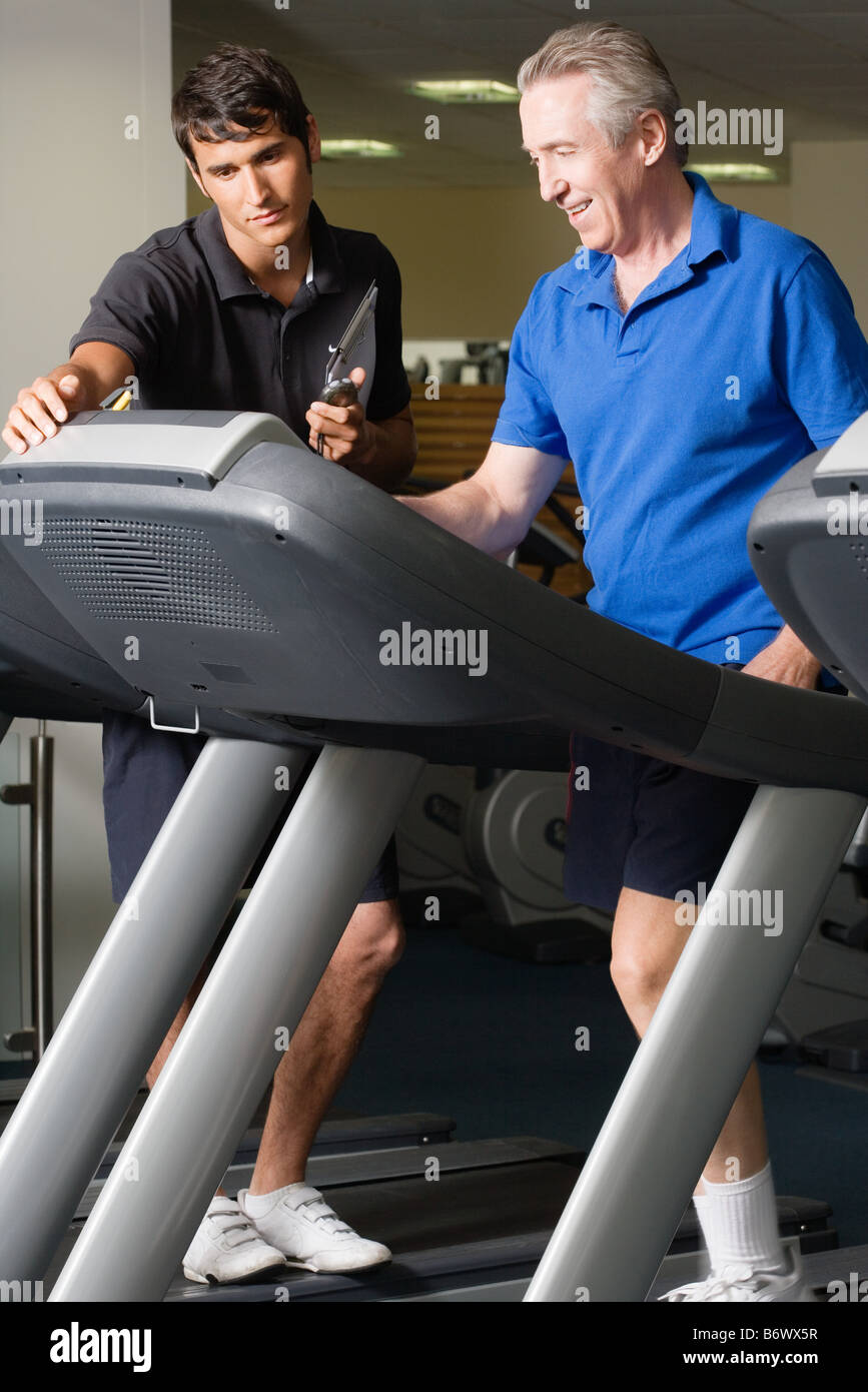 A personal trainer helping a man on a treadmill Stock Photo - Alamy