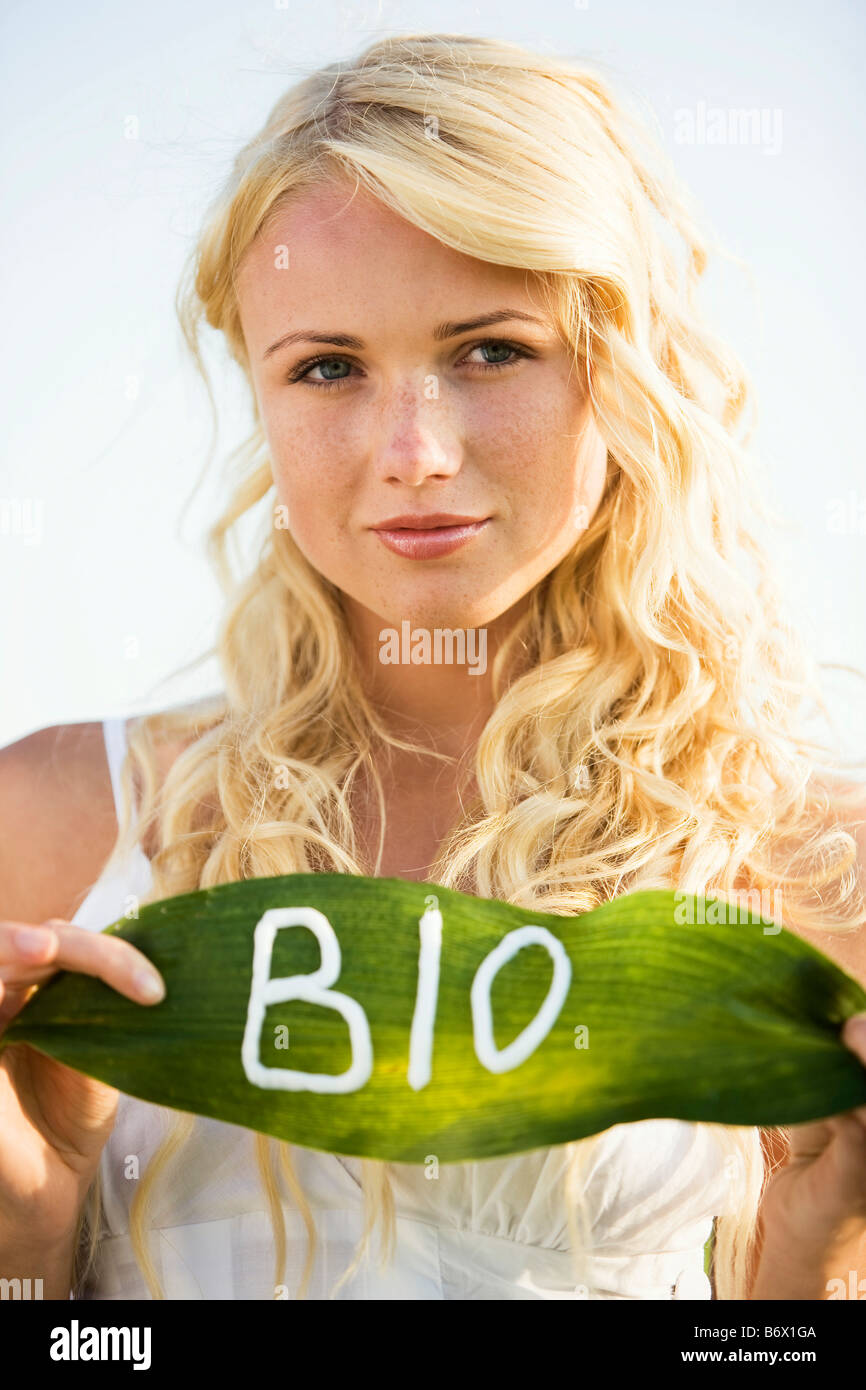 Young woman holding a leaf with "BIO" lettering Stock Photo - Alamy