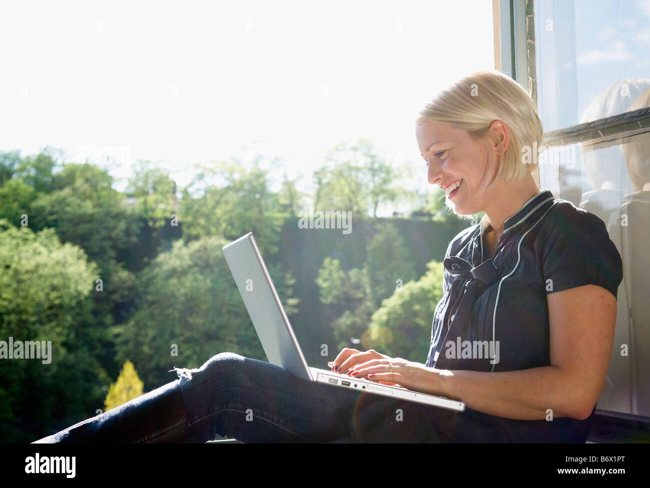 Girl sitting outside with computer Stock Photo - Alamy