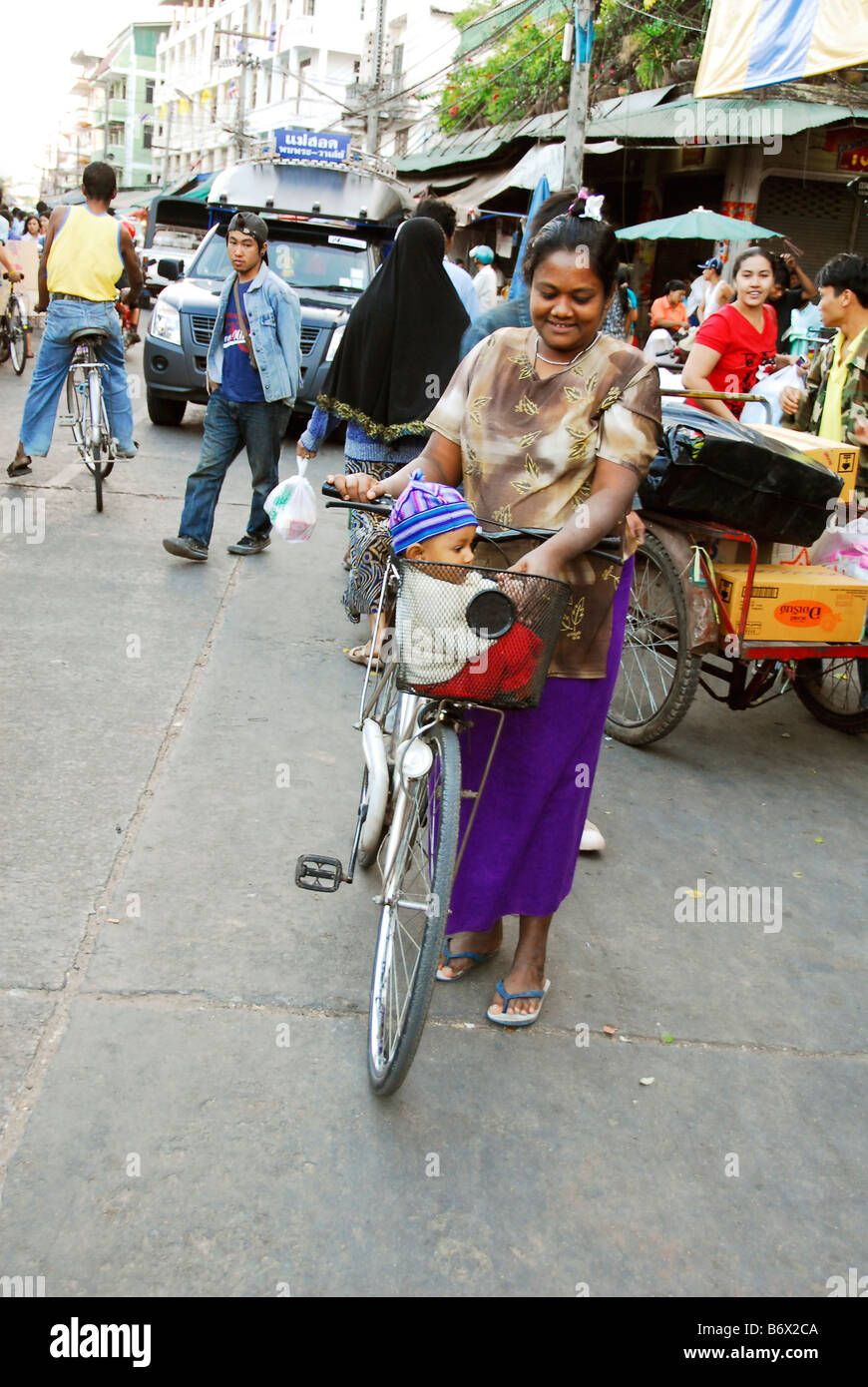 Lady pulling bicycle along her side with babe in bicycle's basket ...