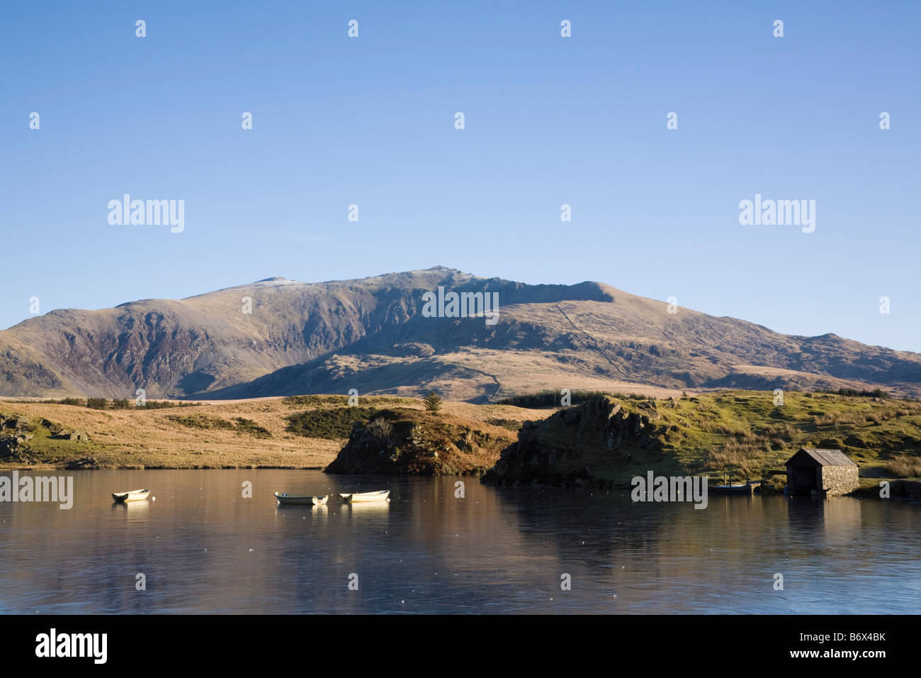Mount Snowdon across frozen Llyn y Dywarchen lake in winter in ...