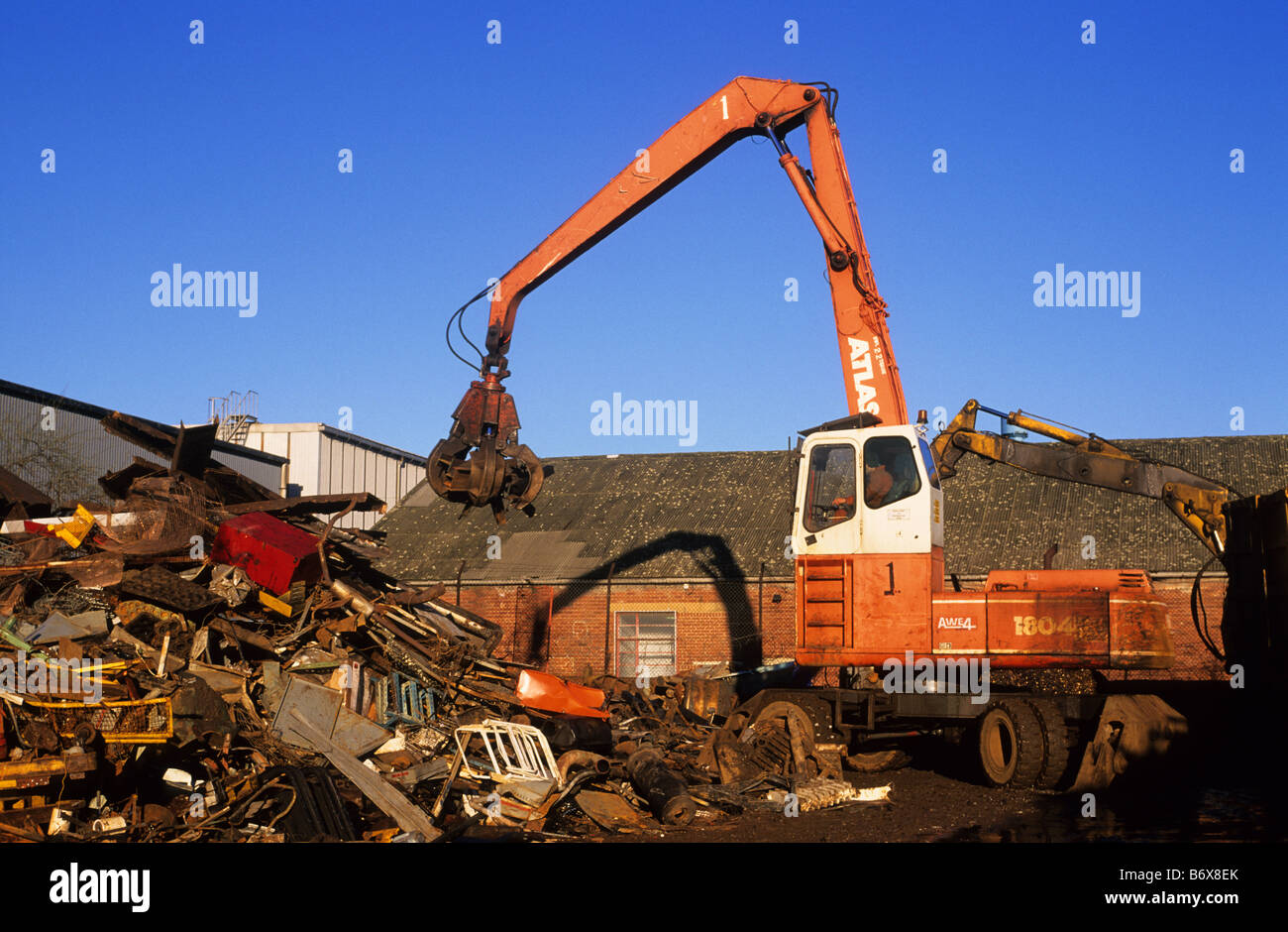 hydraulic crane sorting through scrap metal for recycling at yard UK ...