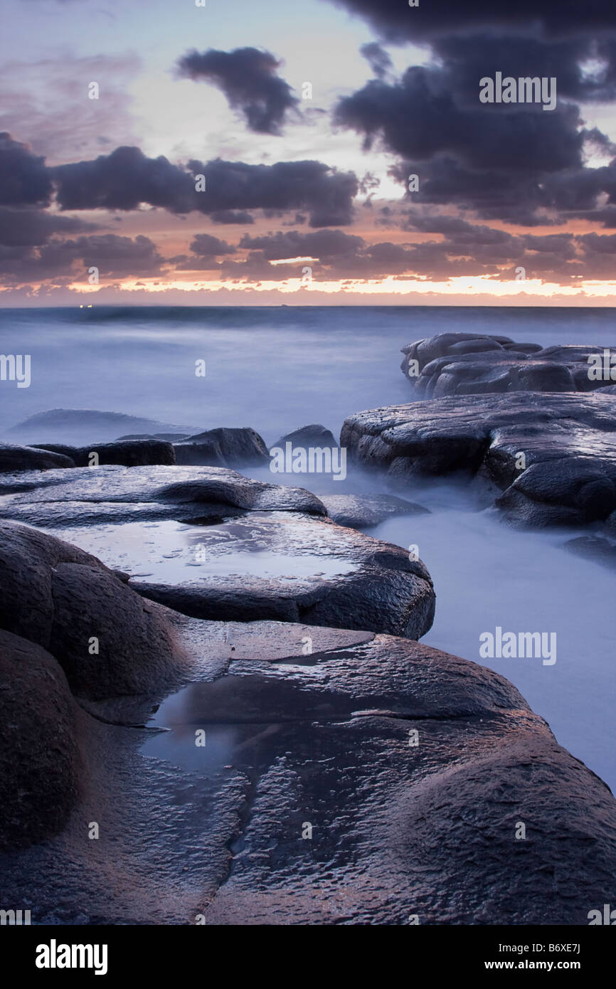 A long exposure taken at sunrise of beach rock and misty ocean from Pt ...