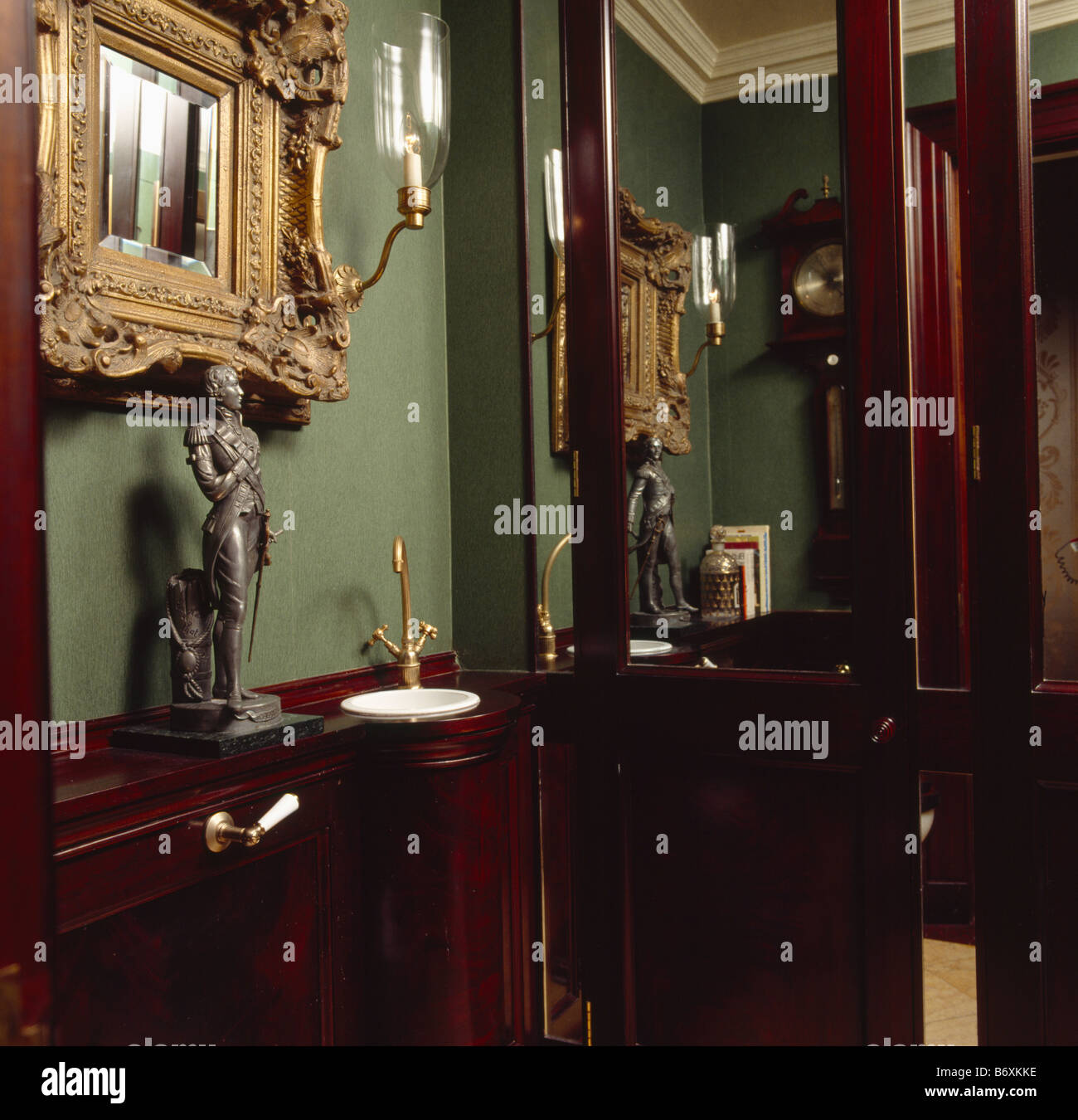Ornate gilt mirror and bronze statue on shelf above corner basin in ...