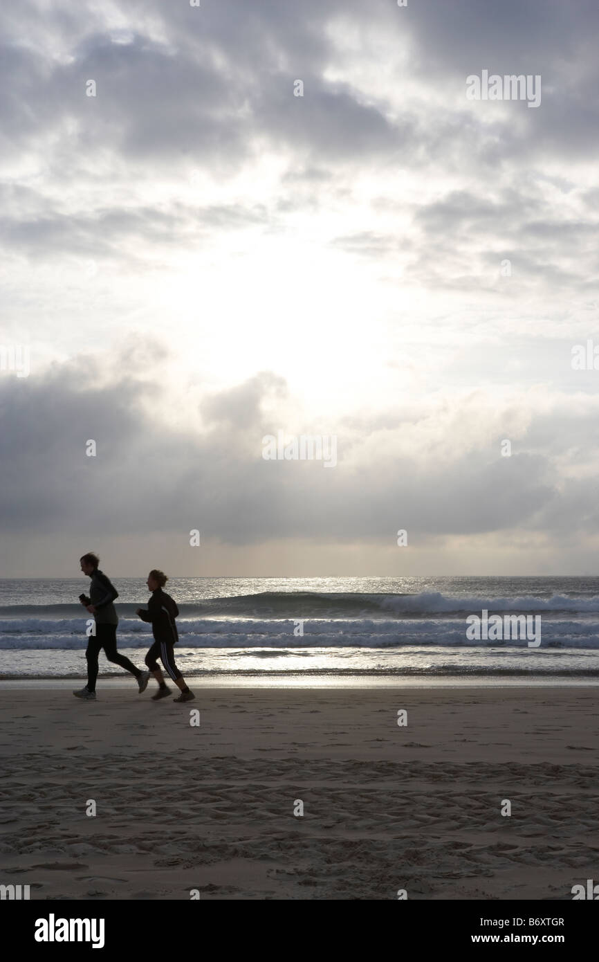 Couple running on a beach at sunset Stock Photo - Alamy