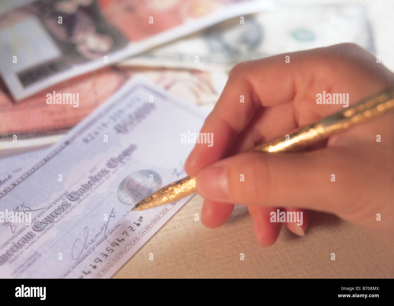 A hand holding a pen signing a check Stock Photo - Alamy