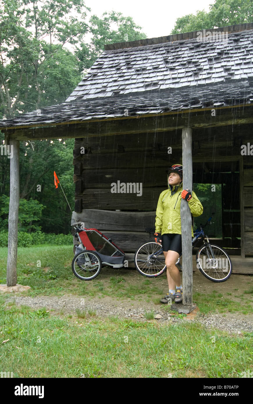 Woman standing under porch roof away from the rain while biking the ...
