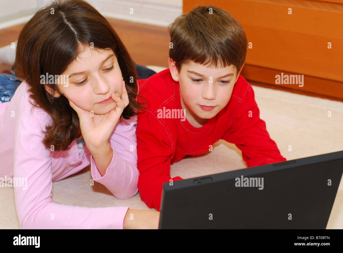 Children lying on the carpet with portable computer Stock Photo - Alamy