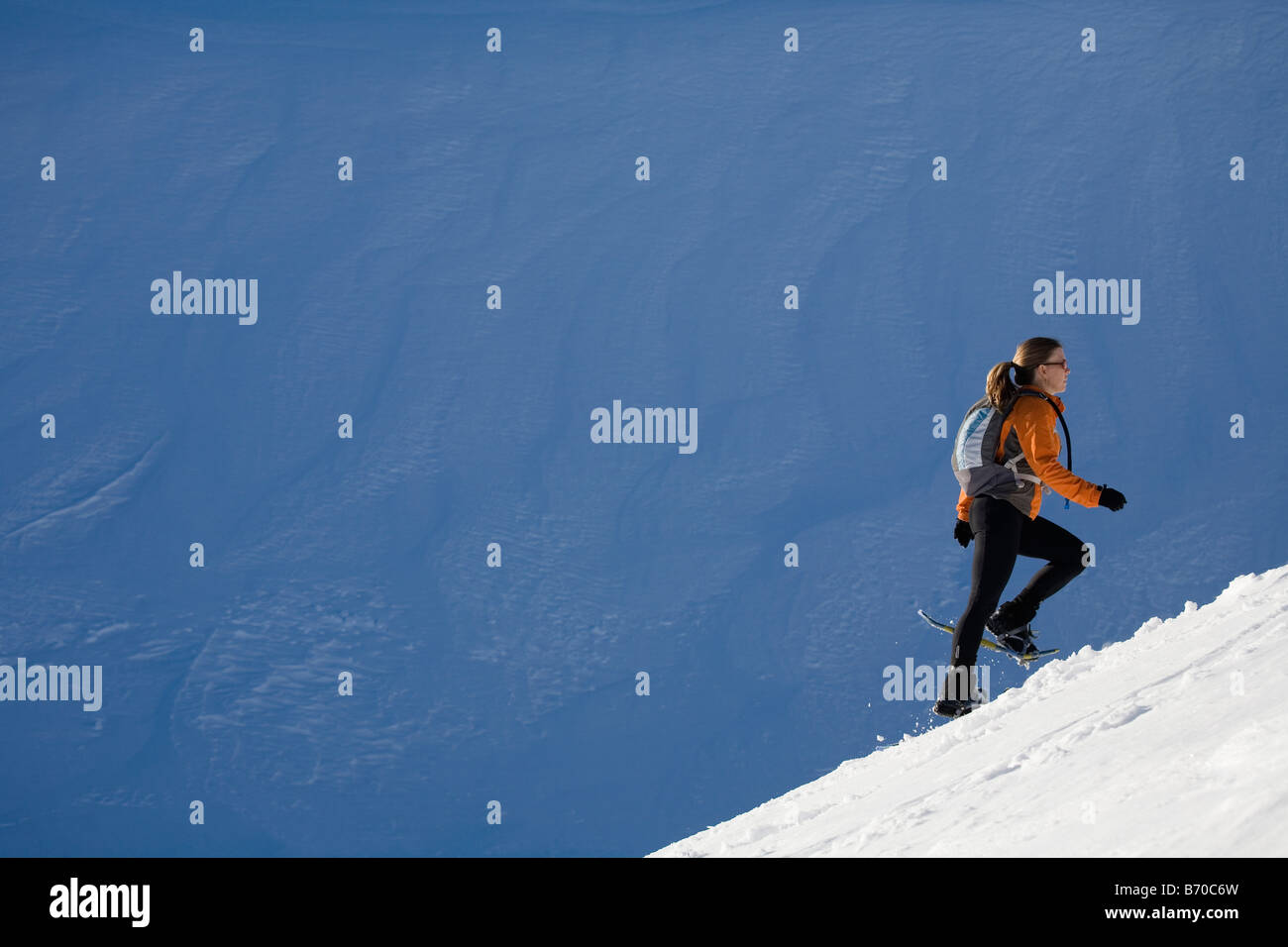 Woman walks uphill in snowshoes Stock Photo - Alamy