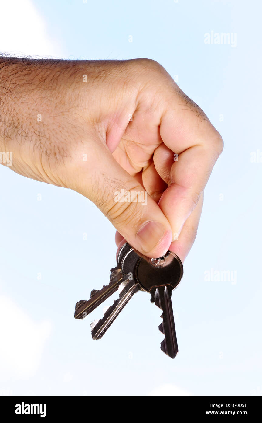 Man s hand holding house keys on blue sky background Stock Photo - Alamy