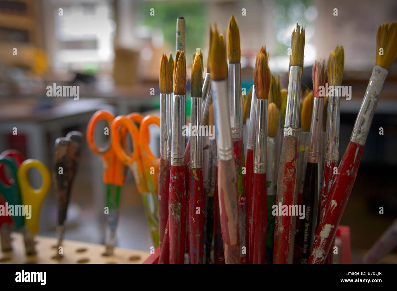 Large bunch of artists paint brushes and scissors in school art room ...