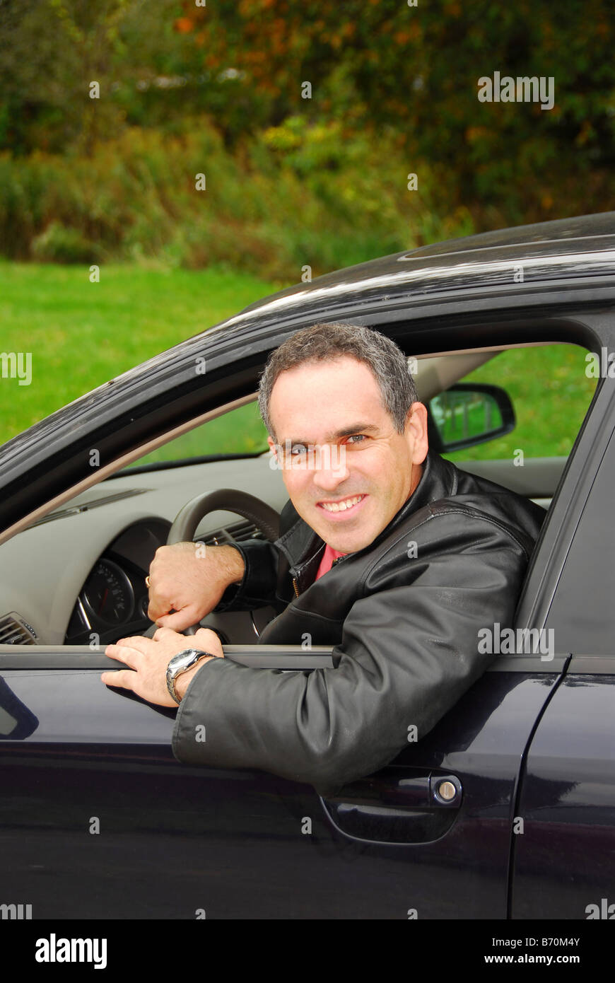 Smiling man looking out of a car window Stock Photo - Alamy