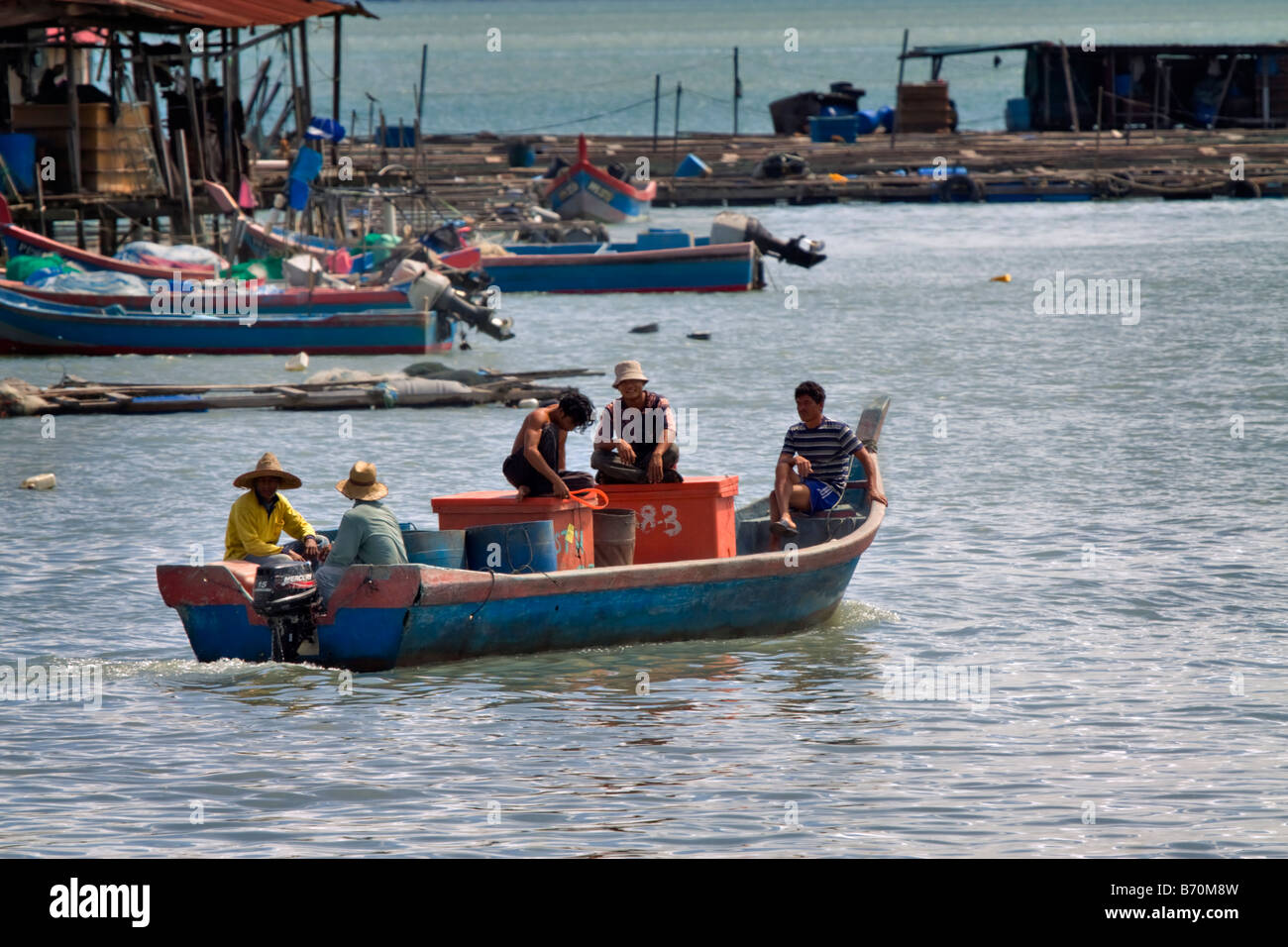 Five men setting out in a fishing boat from a traditional plank jetty ...