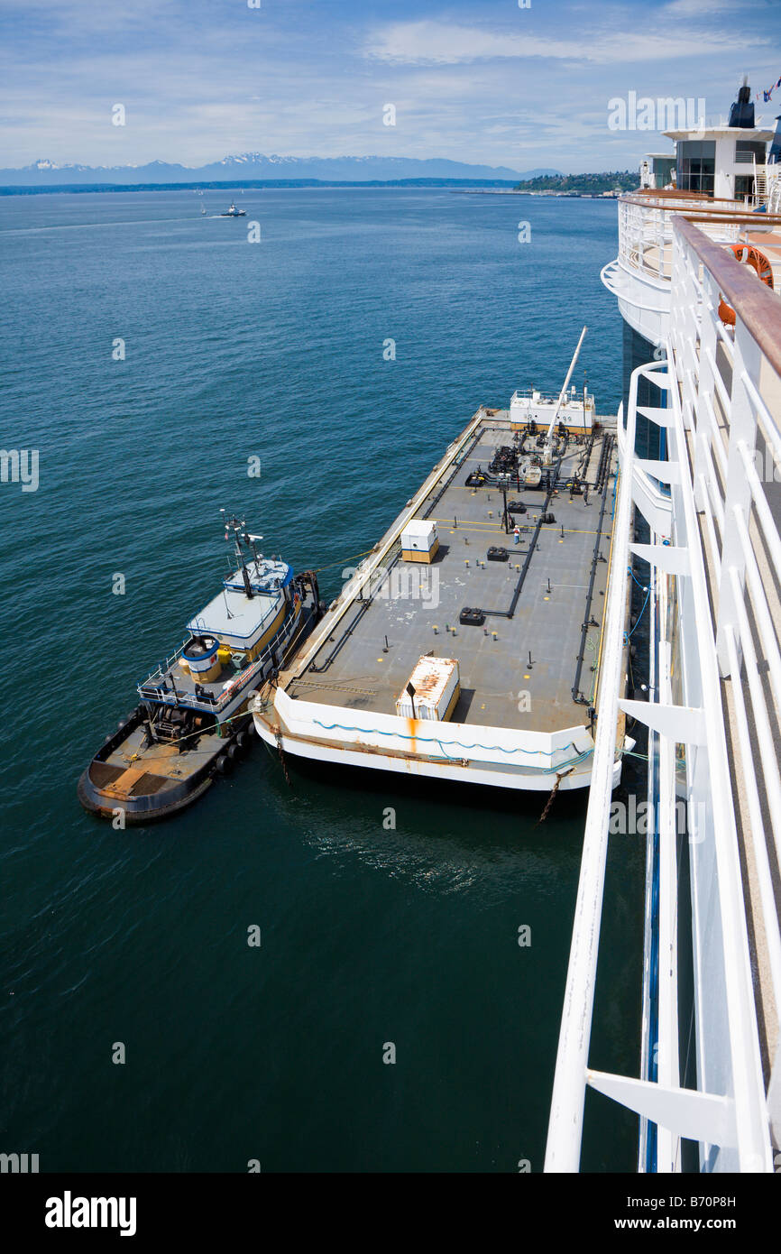 Tug boat tied to fuel barge fueling cruise ship in Elliot Bay at port ...