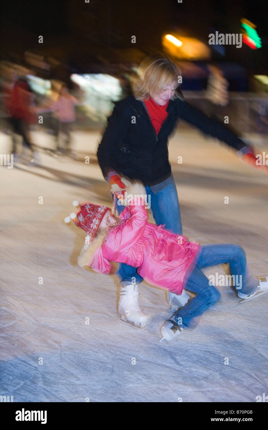 A young girl falling over whilst skating on an artificial ice rink in ...