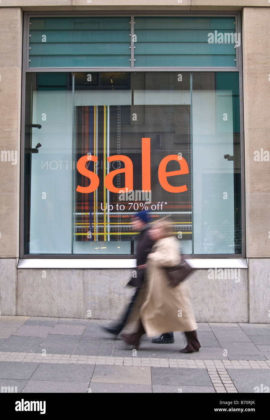 Big sales sign on British High street window shop with shoppers passing ...