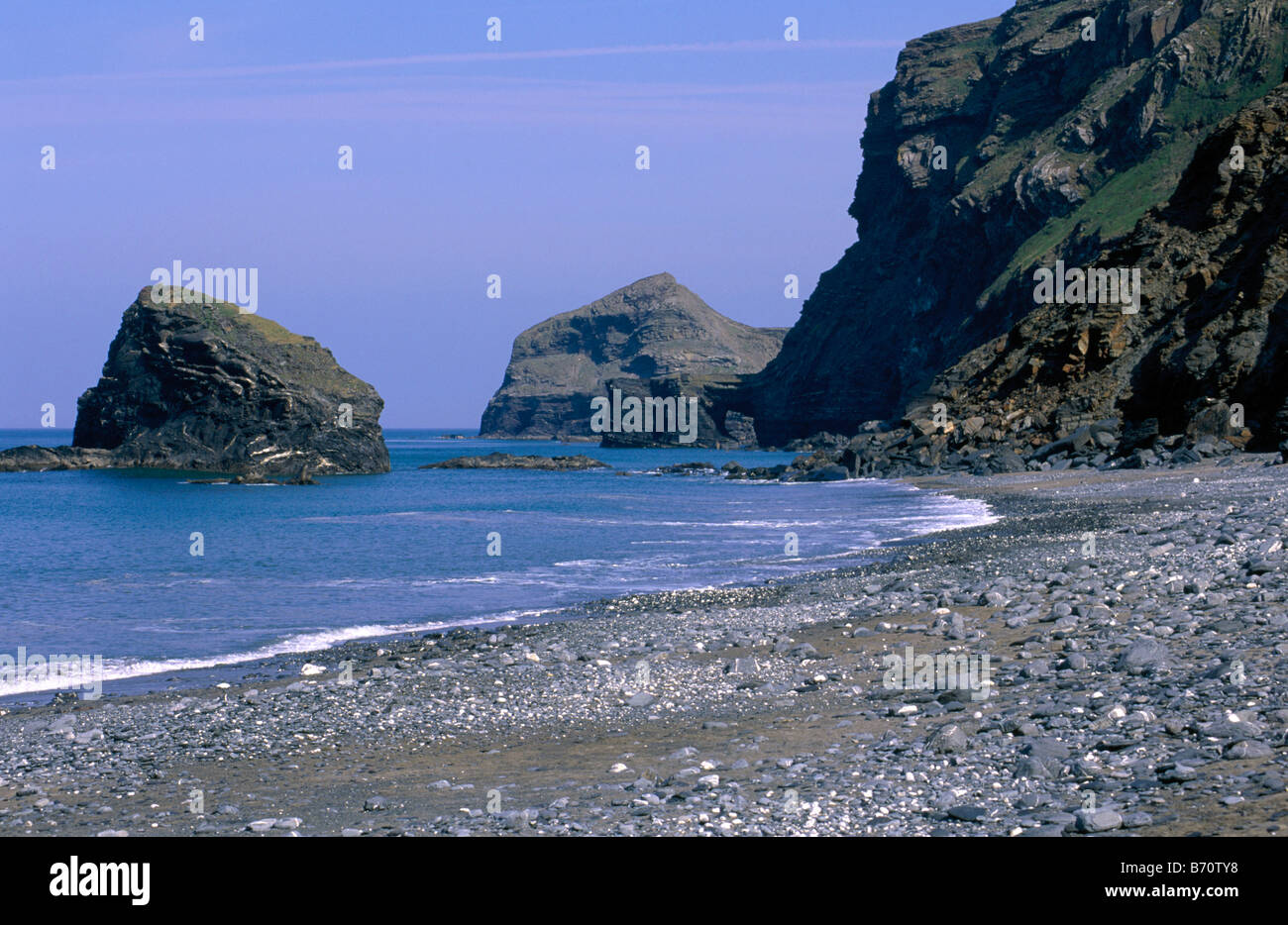 Shingle beach Bright blue sea Waves Rock formations steep sloping ...