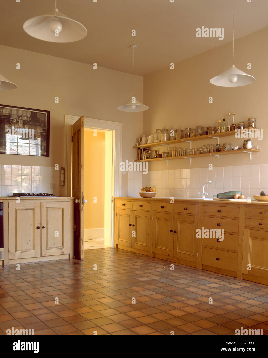 Simple wooden shelves and pine units in economy-style kitchen with ...