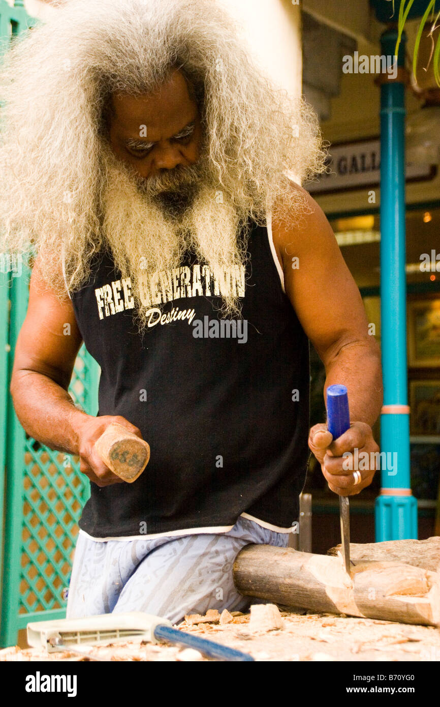 A local artist makes wood carvings for tourists near the harbor in Port ...