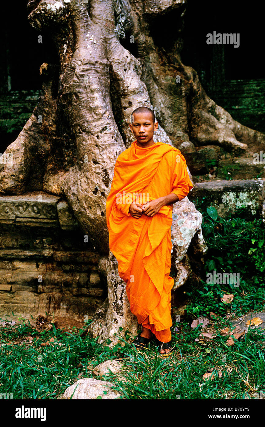 Monk in saffron robes at overgrown and unrestored 12th century Buddhist ...