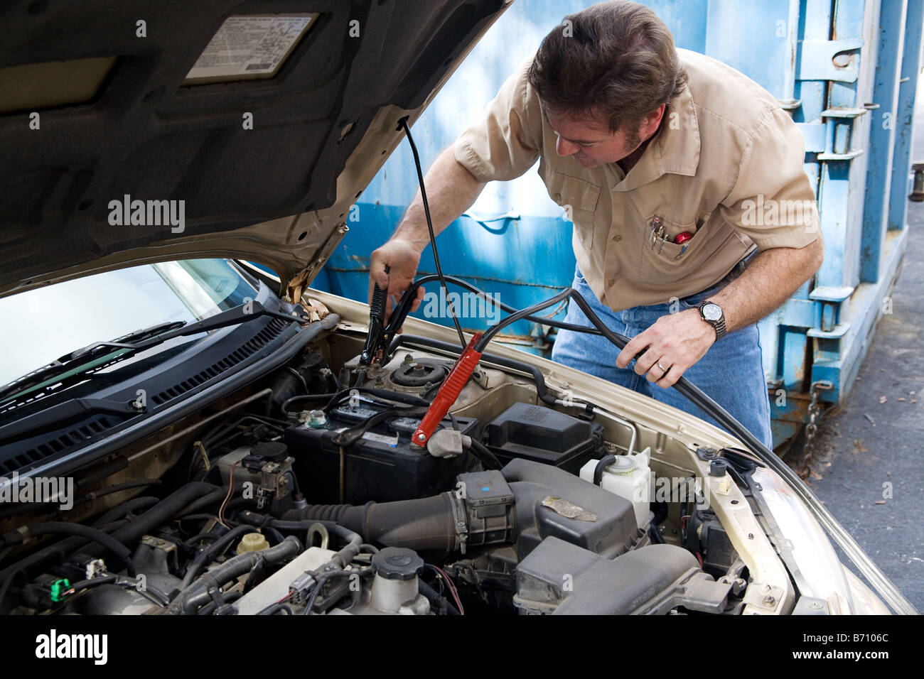 Auto mechanic using jumper cables to charge a car battery Stock Photo ...