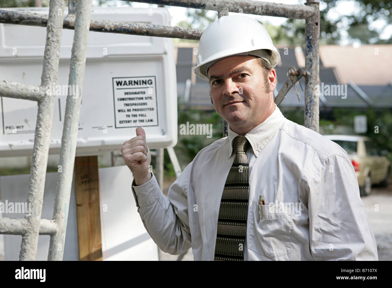 A building inspector standing under scaffolding pointing out the ...
