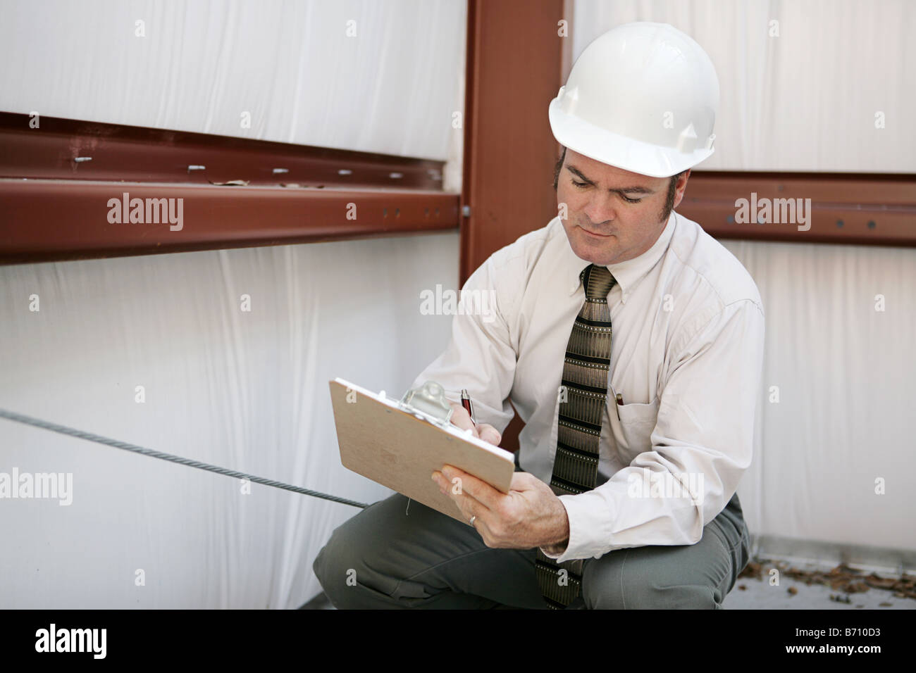A construction inspector on a jobsite making notations on his clipboard ...