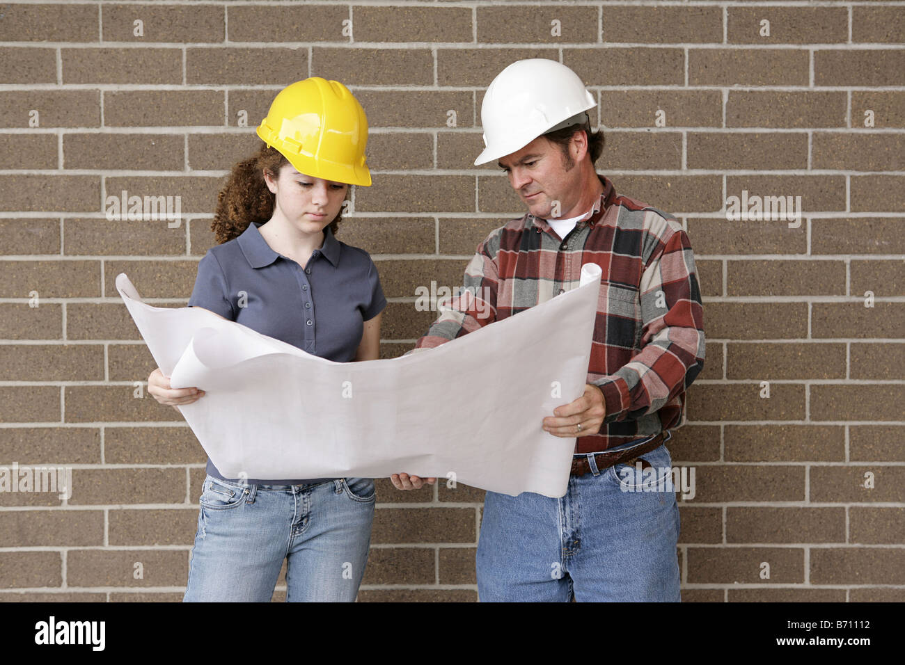A construction foreman going over blueprints with a female apprentice ...