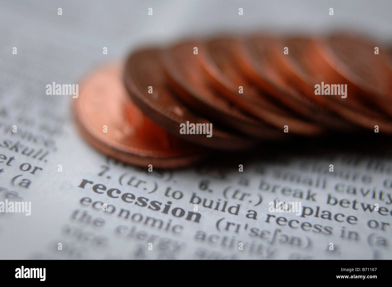 a stack of coins resting on the definition of recession in a dictionary ...