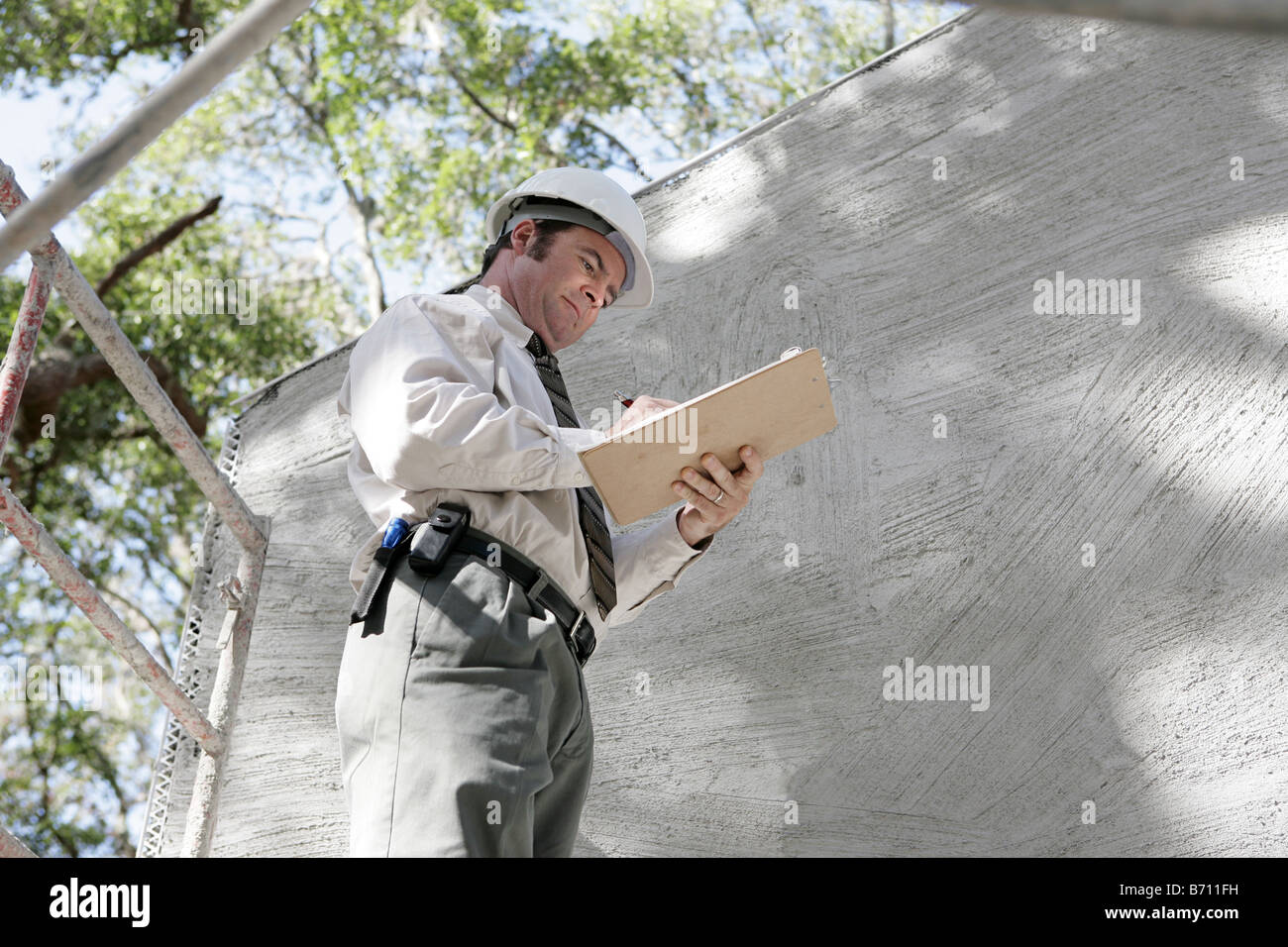 Horizontal view of a construction inspector on scaffolding making notes ...