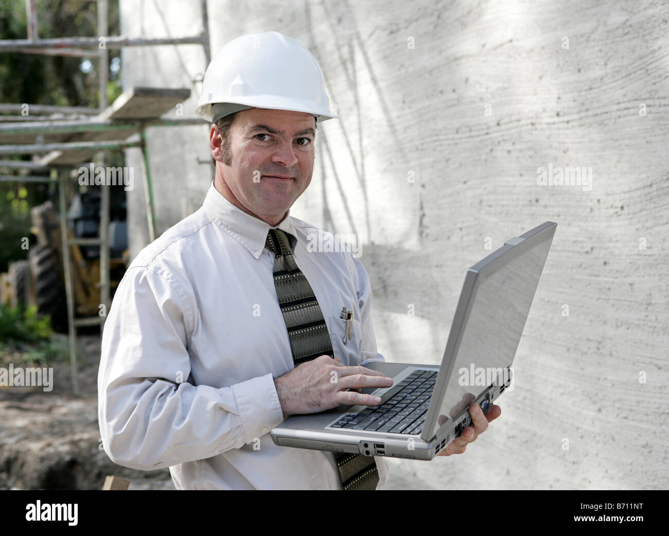 An engineer or building inspector checking building specs on his laptop ...
