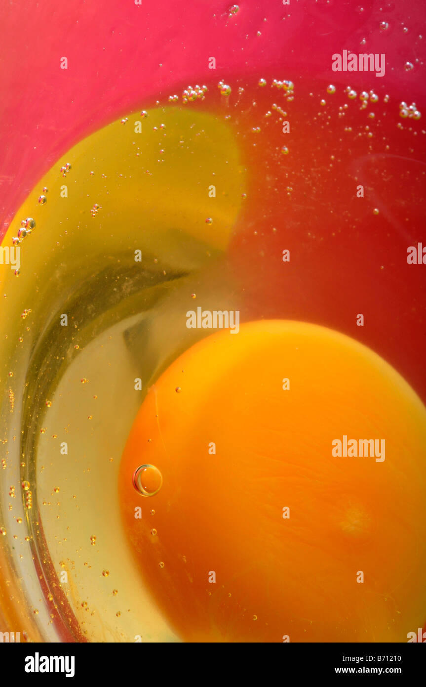 a raw egg in glass yolk yellow white pink orbital Stock Photo - Alamy