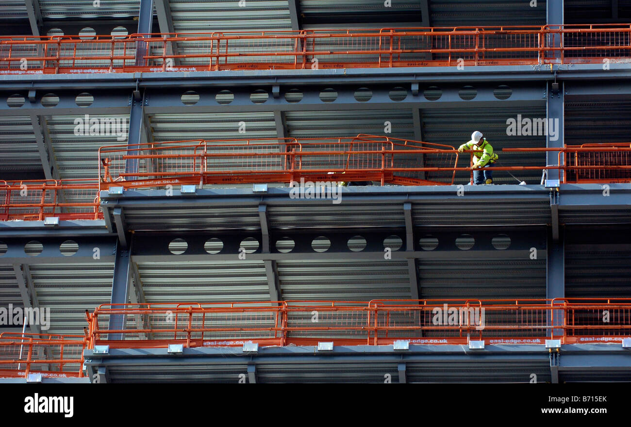 A construction worker puts up safety fencing on an office block under ...