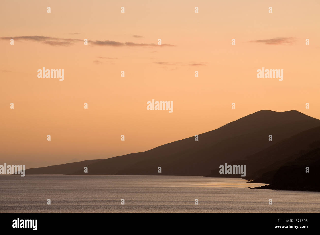 Dingle Peninsula from Inch Strand. The sunset casts a soft glow over ...