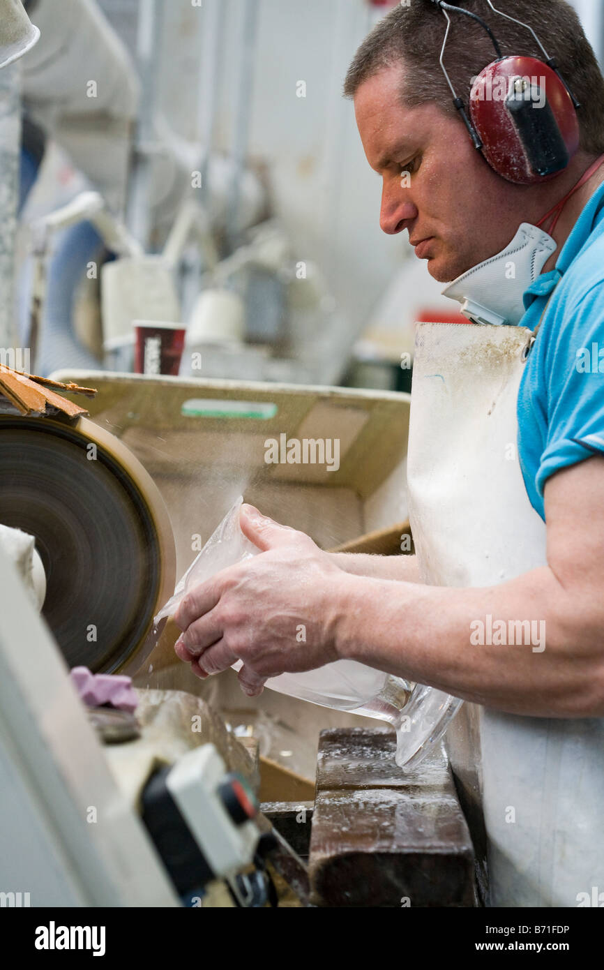 A worker in the crystal factory cuts a precise pattern into a large ...