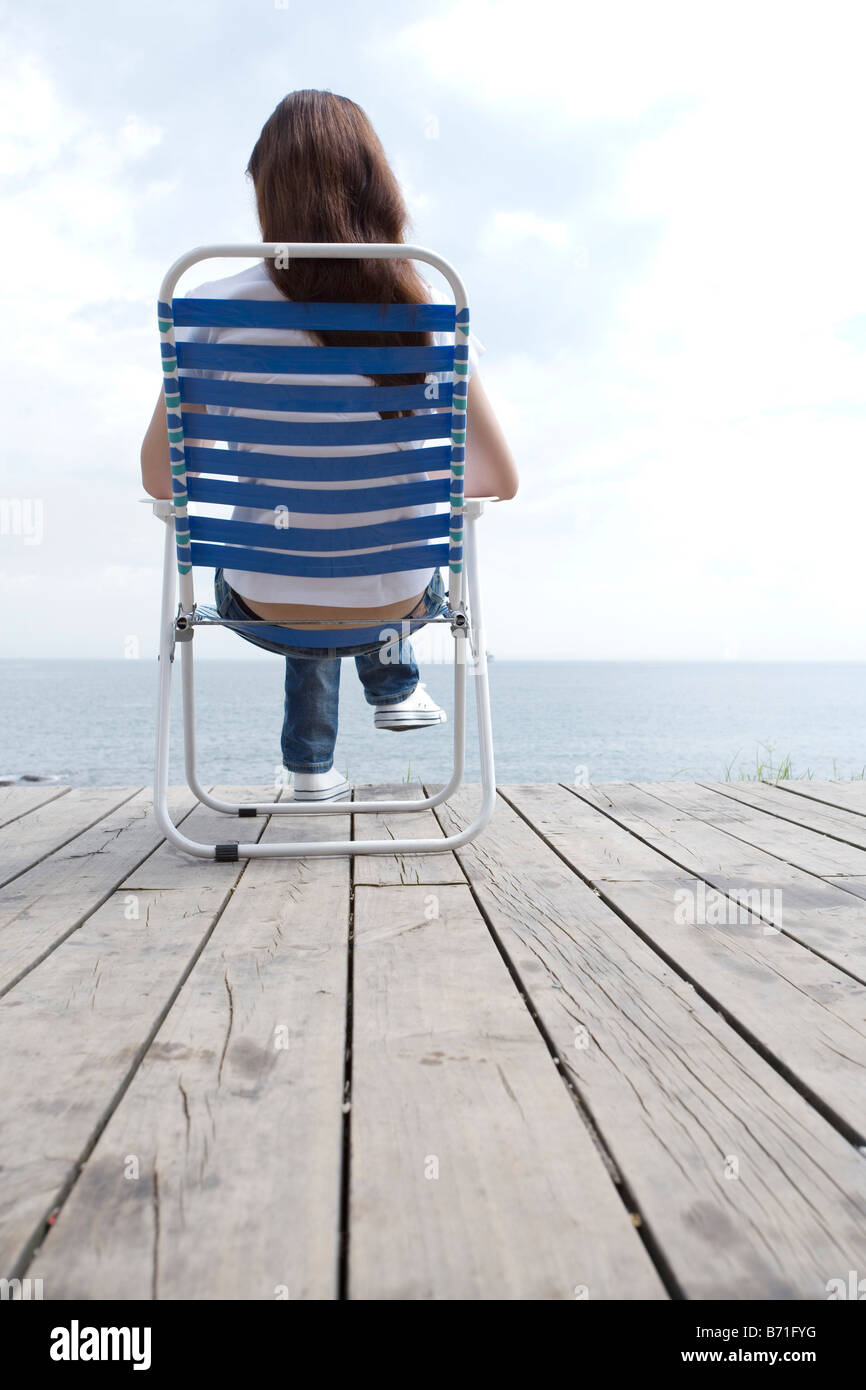 Teenage girl sitting on deckchair rear view Stock Photo - Alamy
