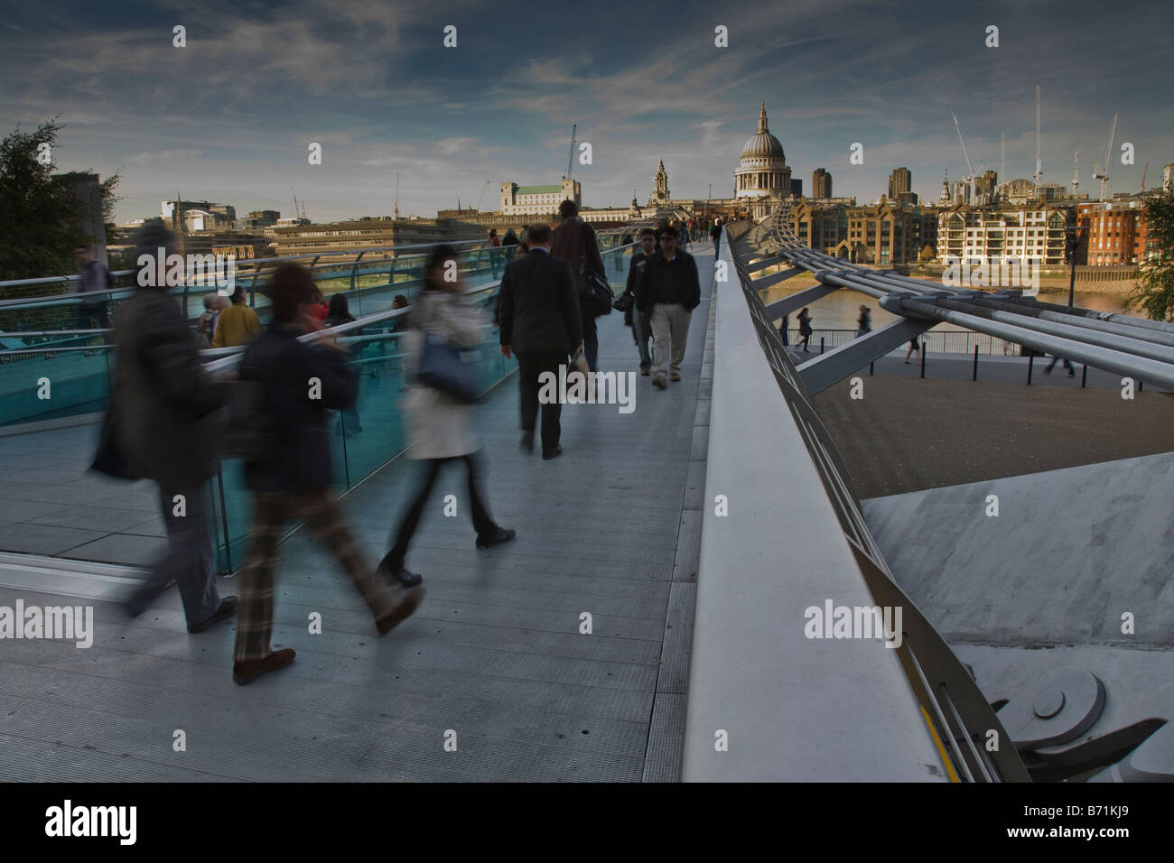 Pedestrians walk across the Millennium Bridge with St Paul's Cathedral ...
