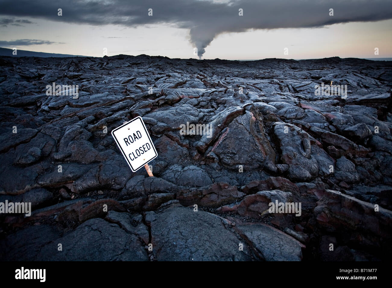 Road sign on road covered in lava with steam clouds from ocean entry in ...