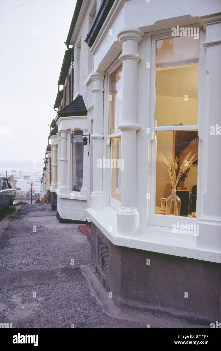 Sideways view of terraced Victorian house with lighted bay window in ...