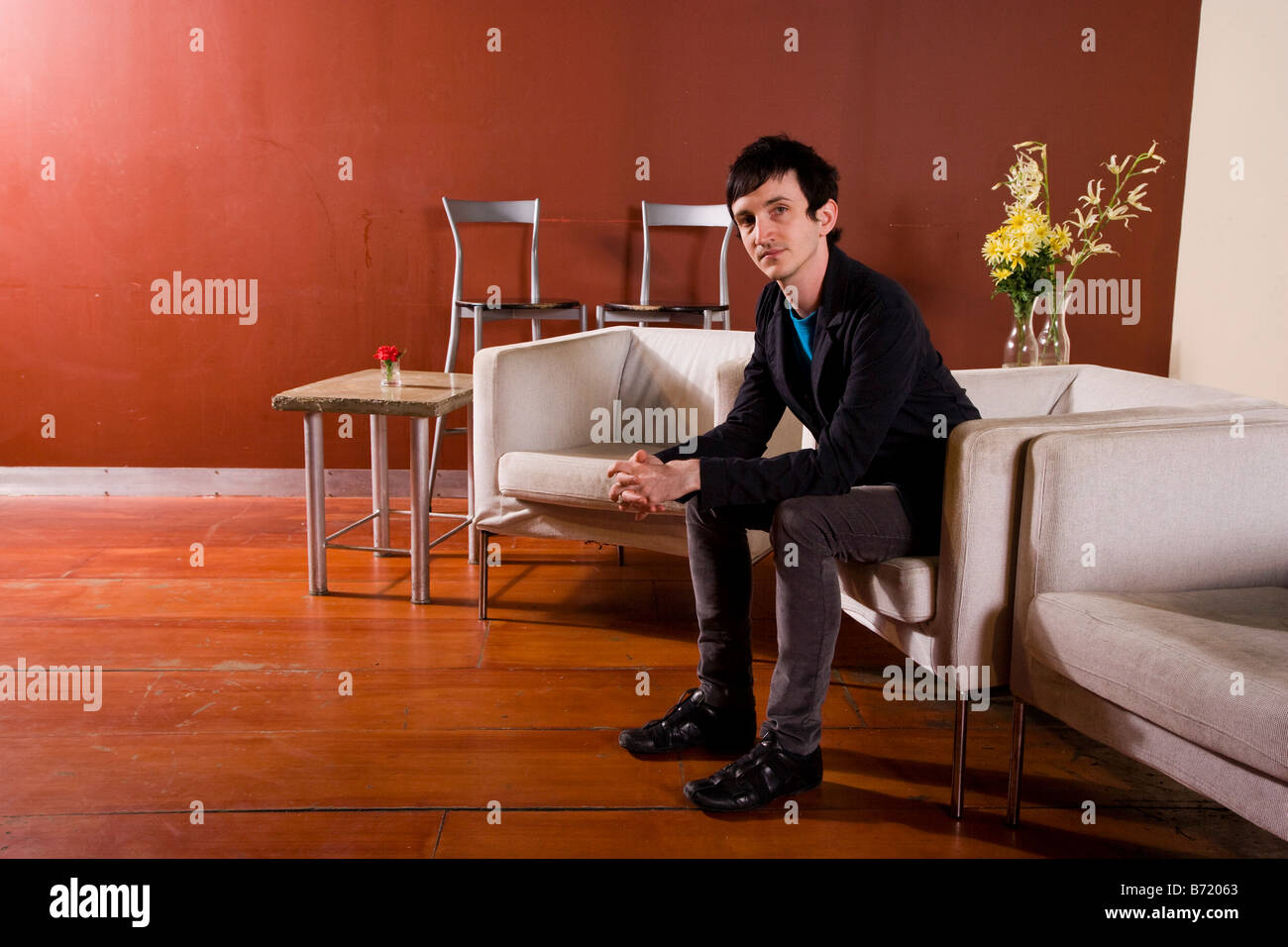 Young stylish man sitting in modern living room Stock Photo - Alamy