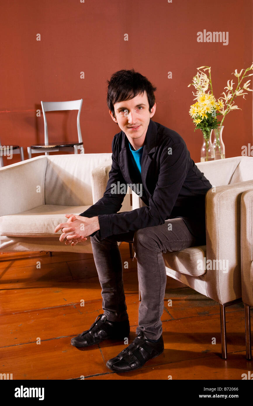 Young stylish man sitting in modern living room Stock Photo - Alamy
