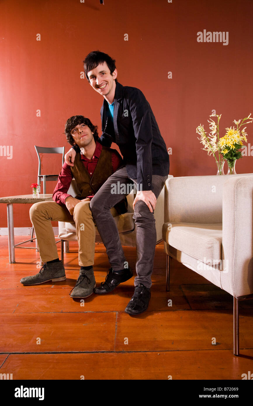 Two young stylish men sitting in modern living room Stock Photo - Alamy