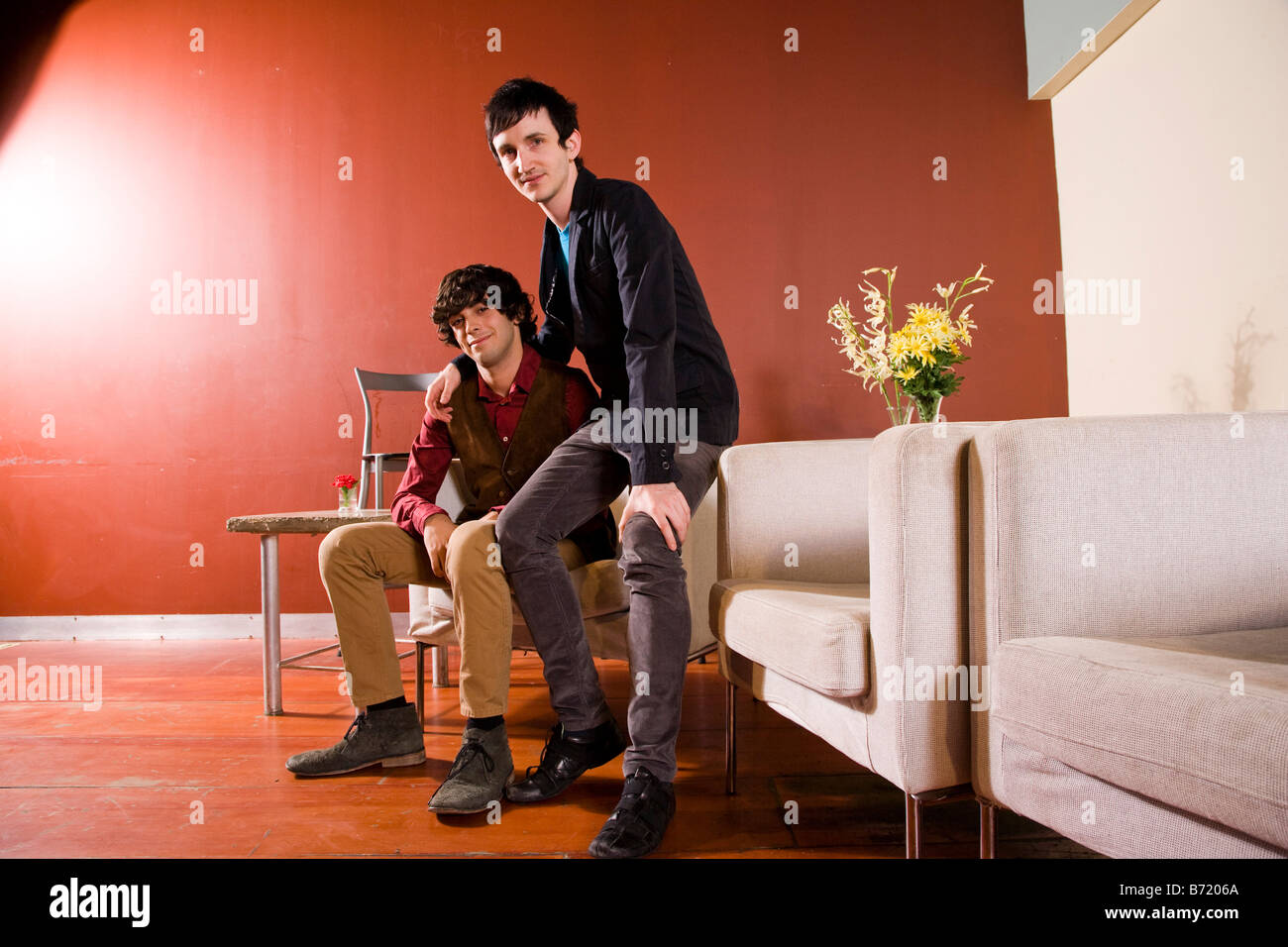 Two young stylish men sitting in modern living room Stock Photo - Alamy
