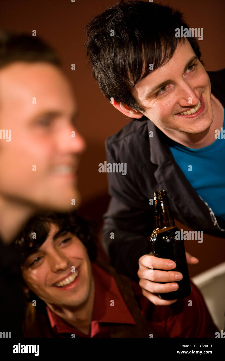 Close-up of three young male friends hanging out and drinking together ...