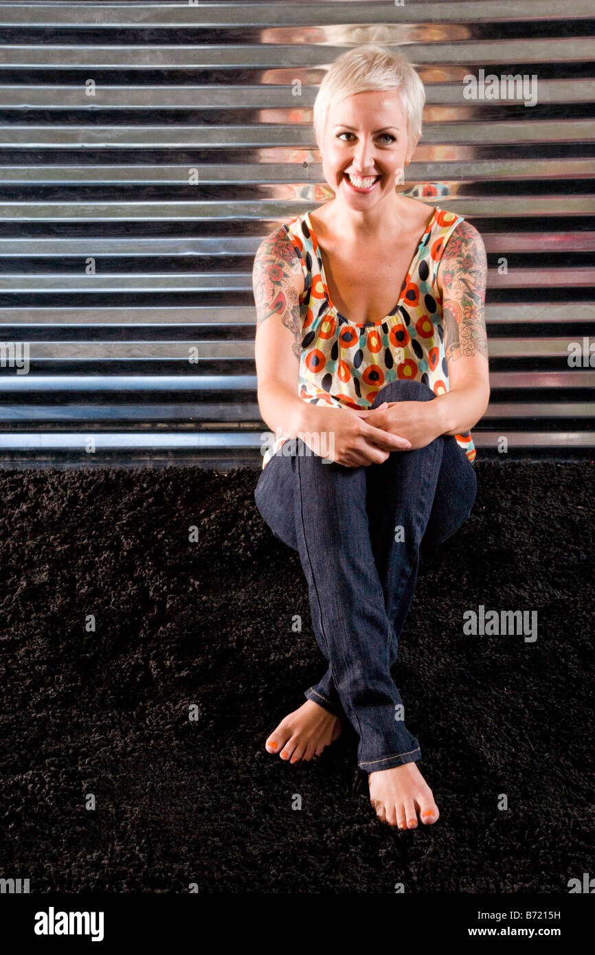 Young woman with tattoo design on arm sitting on floor Stock Photo - Alamy